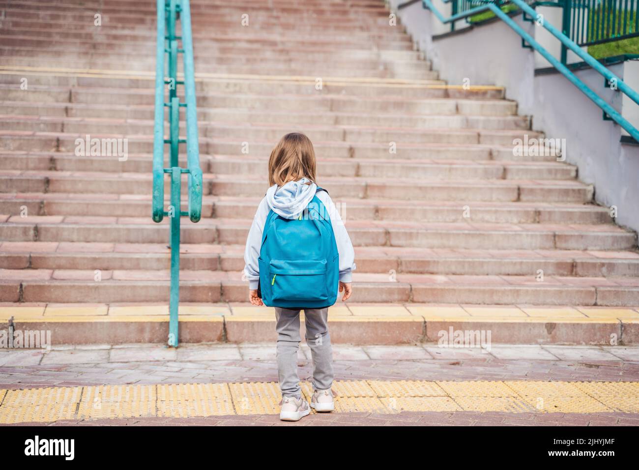 Back to elementary, primary school. Little girl with big backpack goes ...