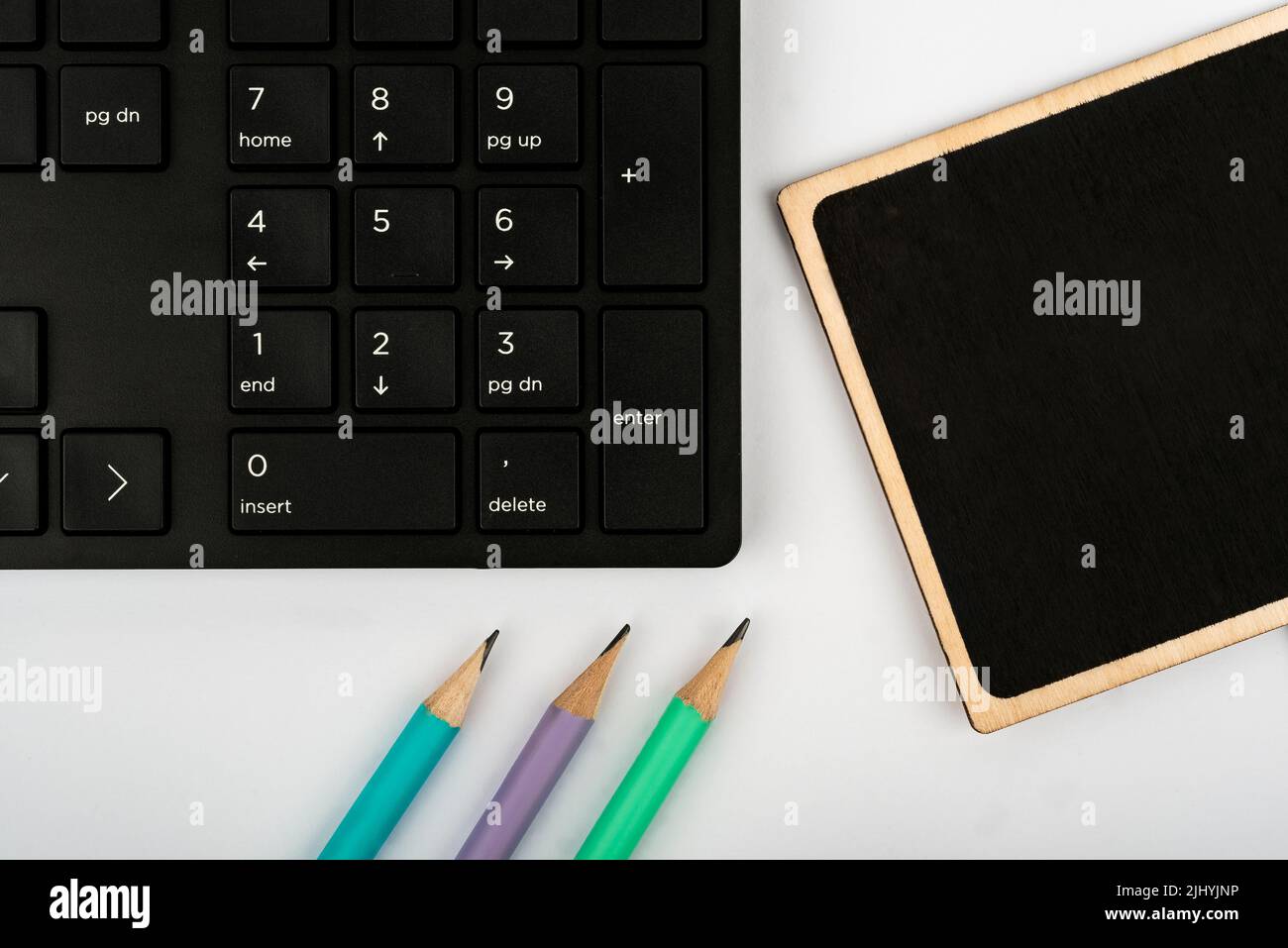 A part of a black computer keyboard, a paper and pencils isolated on a ...