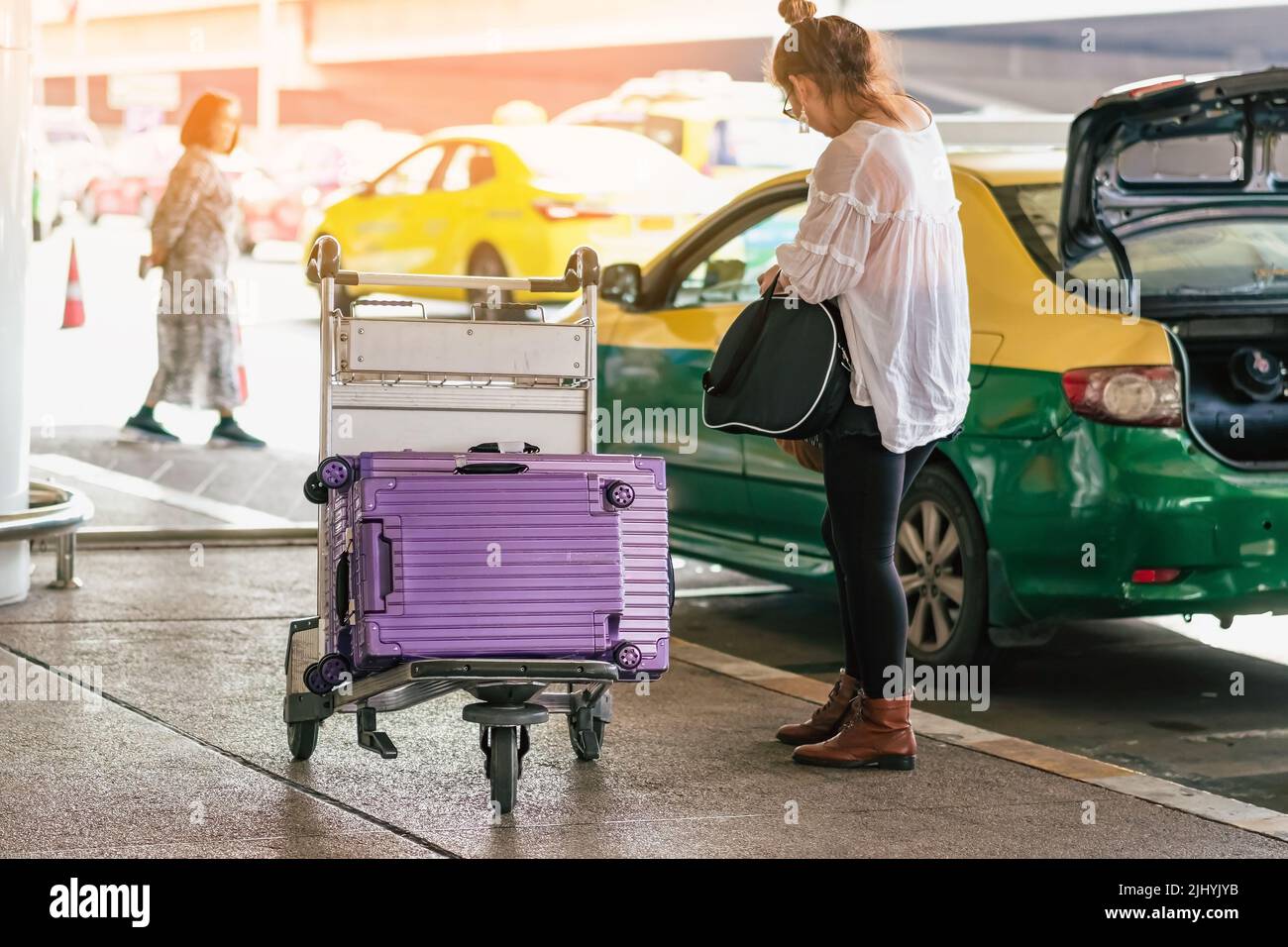 Back view of Asian female passenger with big roller luggage stand to ...
