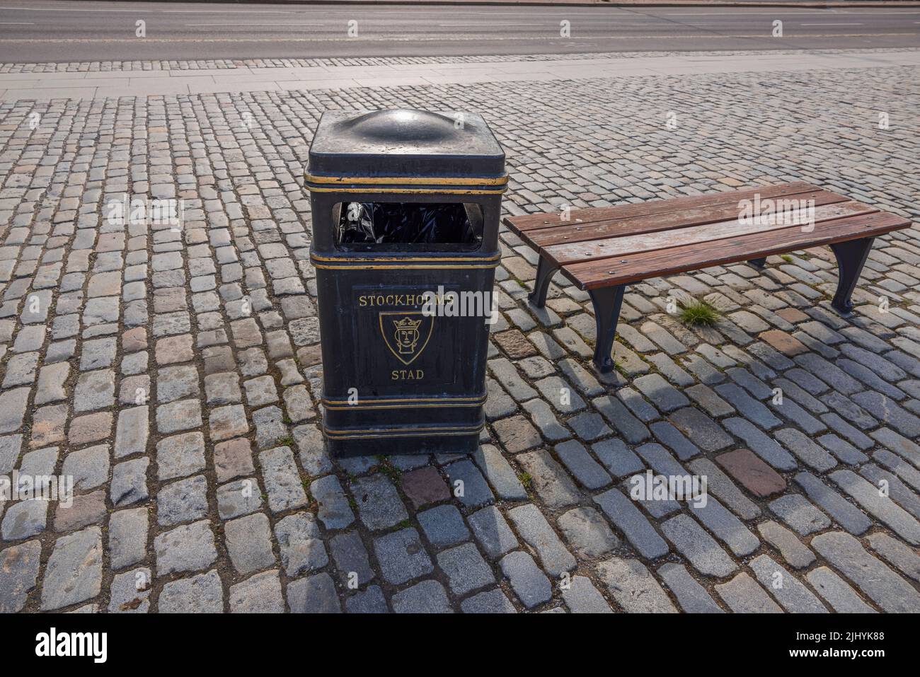 Close up view of garbage bin near bench on square covered with stone ...