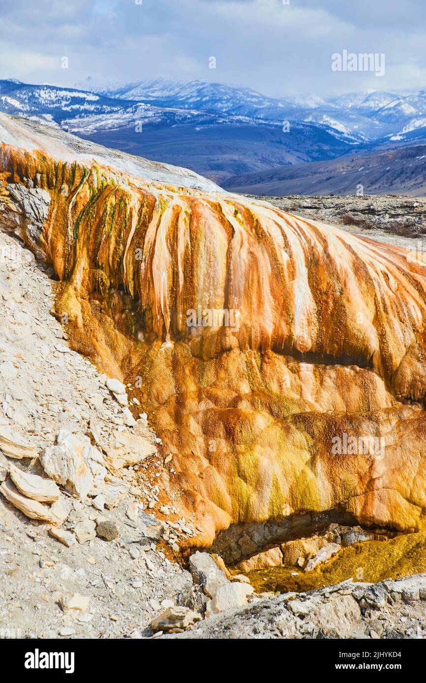 Waves of warm colors from Yellowstone mound by snowy mountains Stock ...