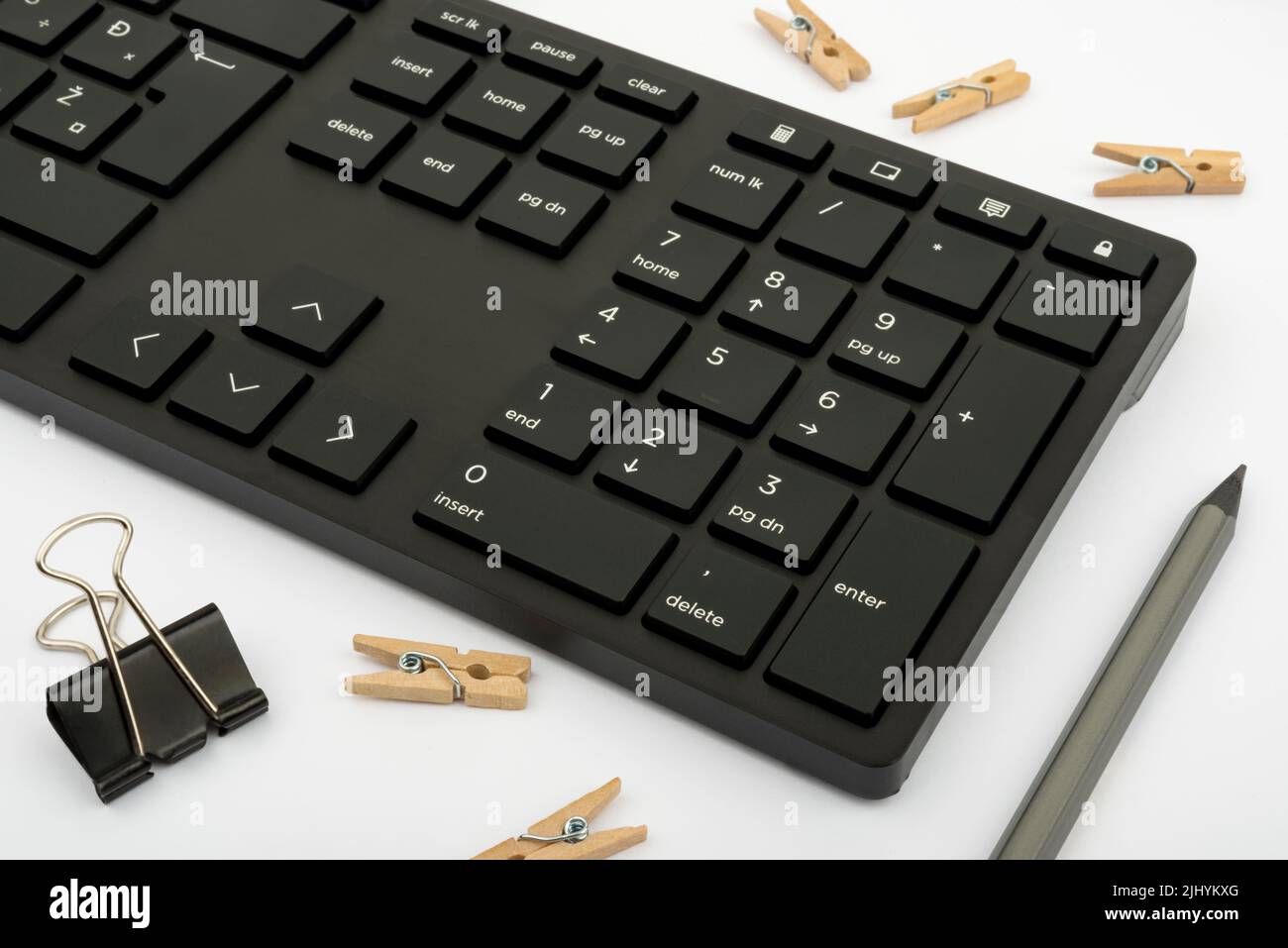 A closeup of a computer keyboard with office stationery on a white ...