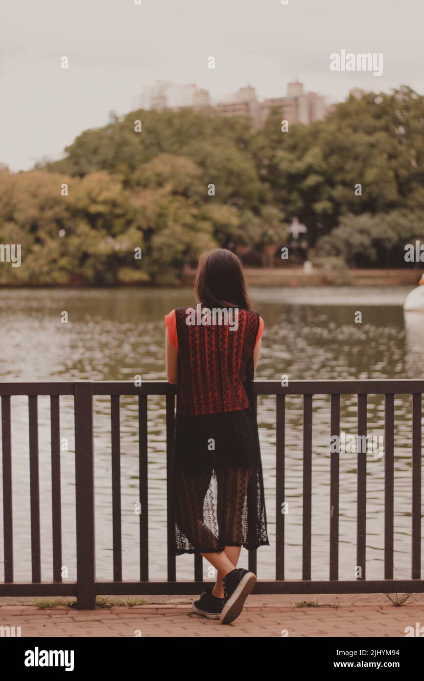 back view of young woman looking at the calm lake on the balcony Stock ...