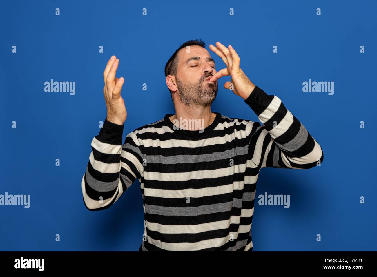 Happy business man licking fingers isolated on trendy blue studio ...