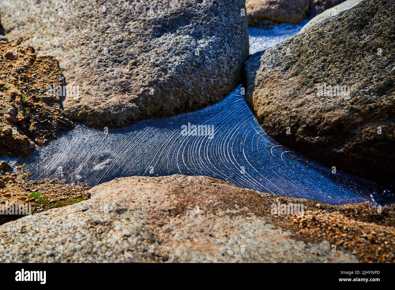 Unusual wavy ice pattern between rocks in detail Stock Photo - Alamy
