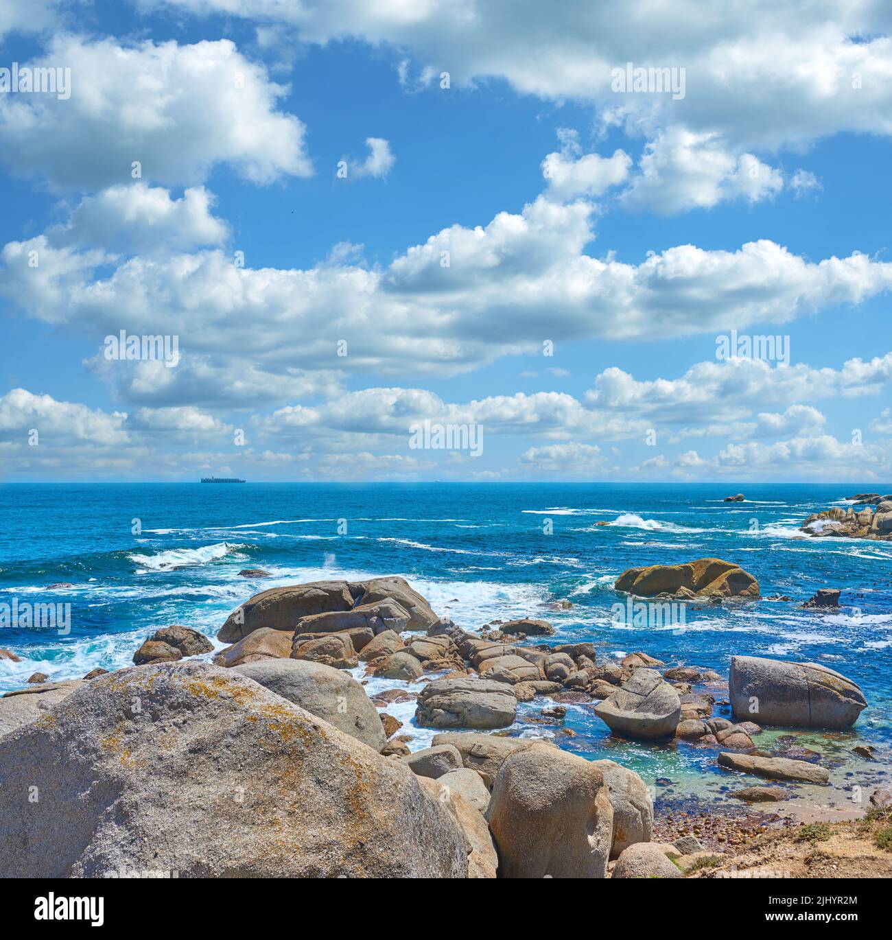 Rocks in the ocean under cloudy blue sky background with copy space ...