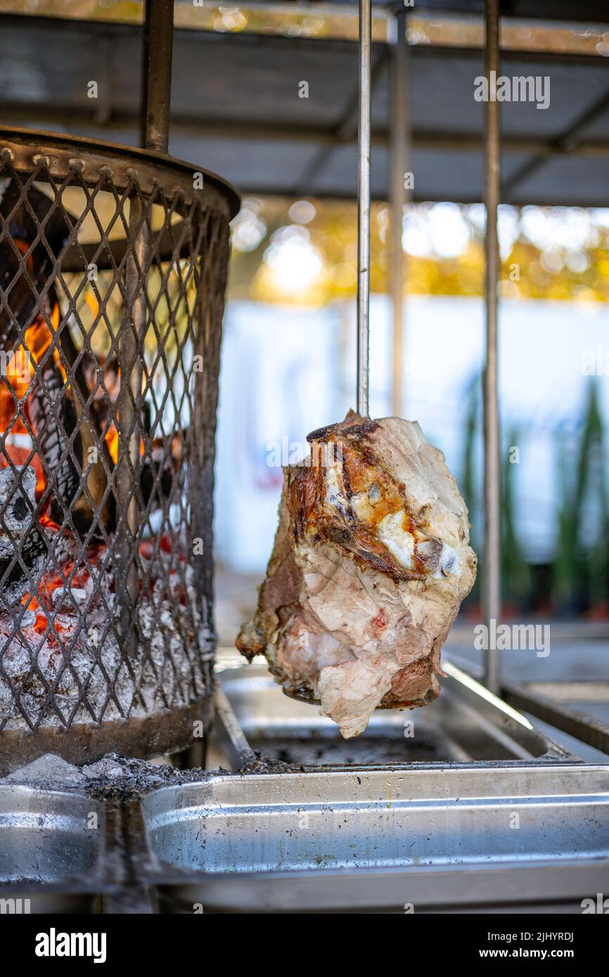Pork ham barbecue grilled over a wood fire. Rotating vertical ...