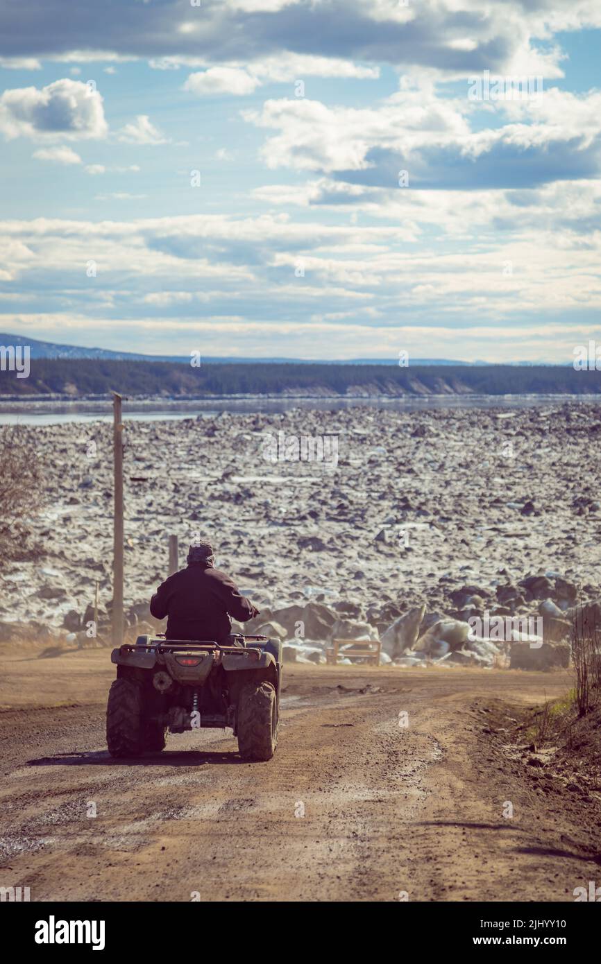 Man driving an ATV on dirt road in northern Indigenous community of ...