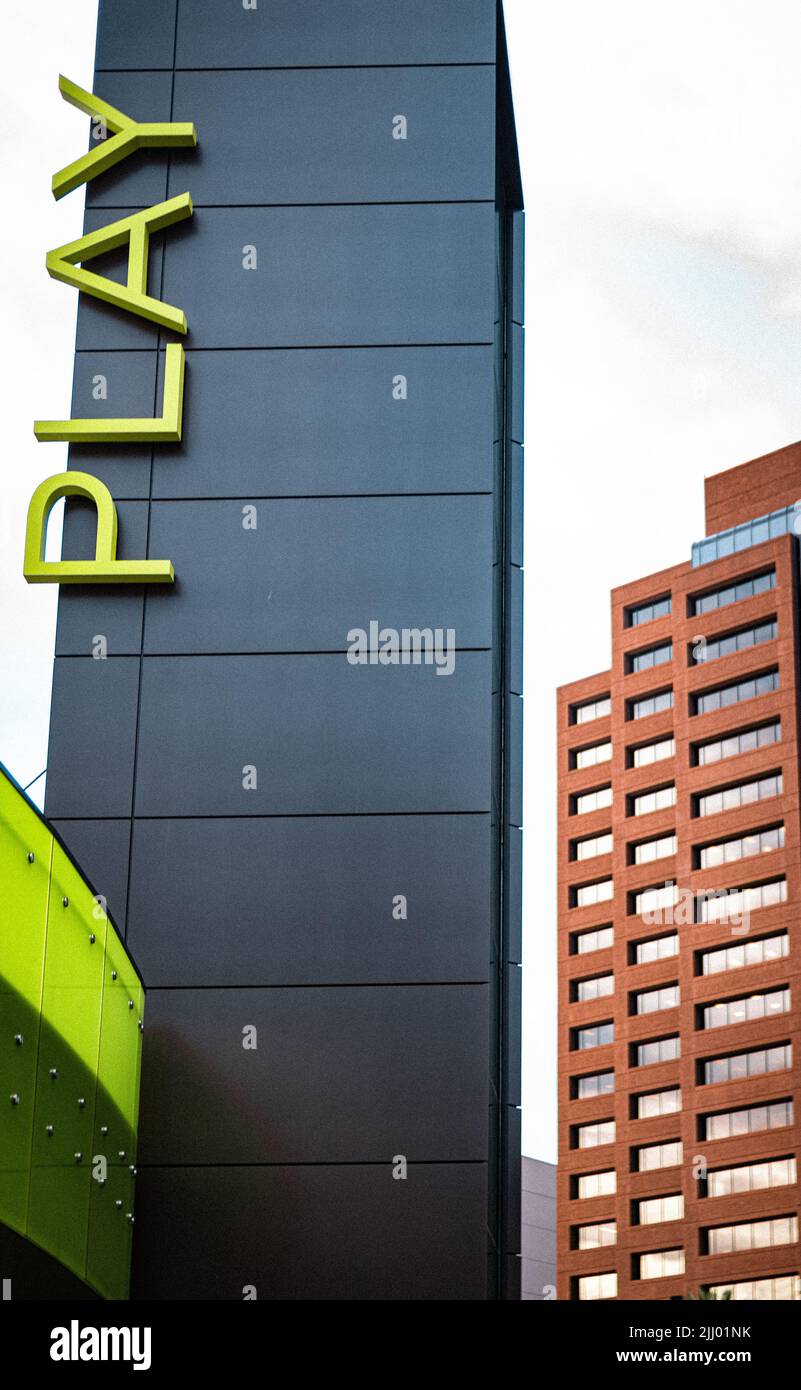 A vertical shot of the facade of a modern building with neon play ...
