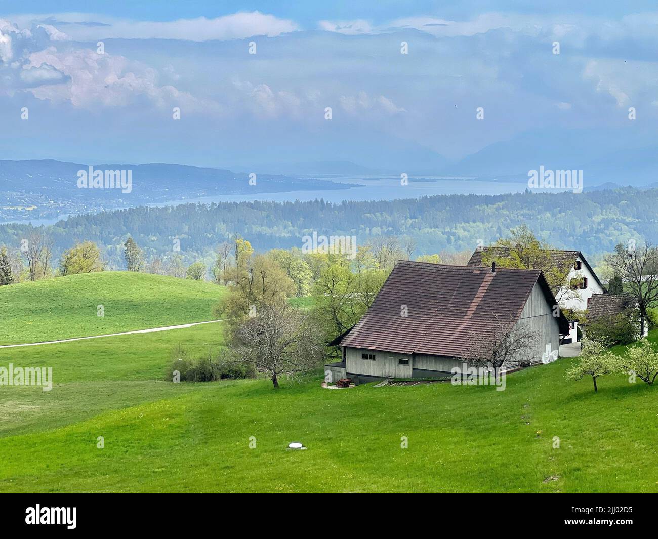 The farm buildings on lush green hill with forests in the background ...