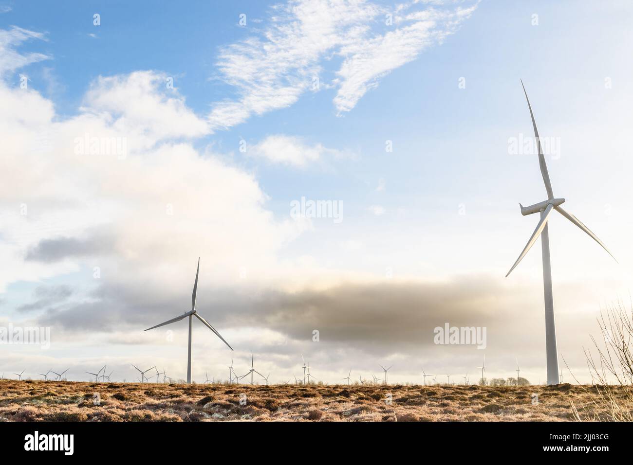 The wind turbines spinning at a wind farm against blue cloudy sky background Stock Photo - Alamy
