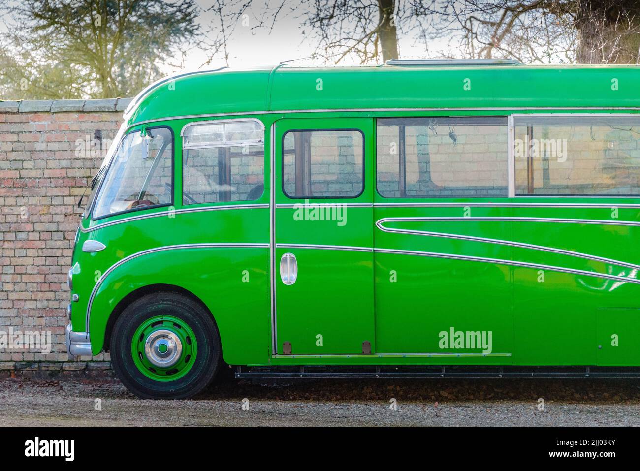 A bright green bus parked in front of brick fence Stock Photo - Alamy