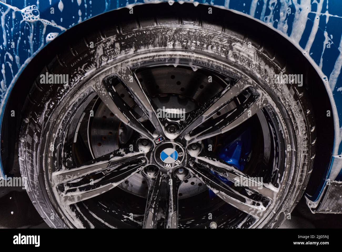 BMW M2 wheel in a car wash, all covered with foam. Car detailing ...