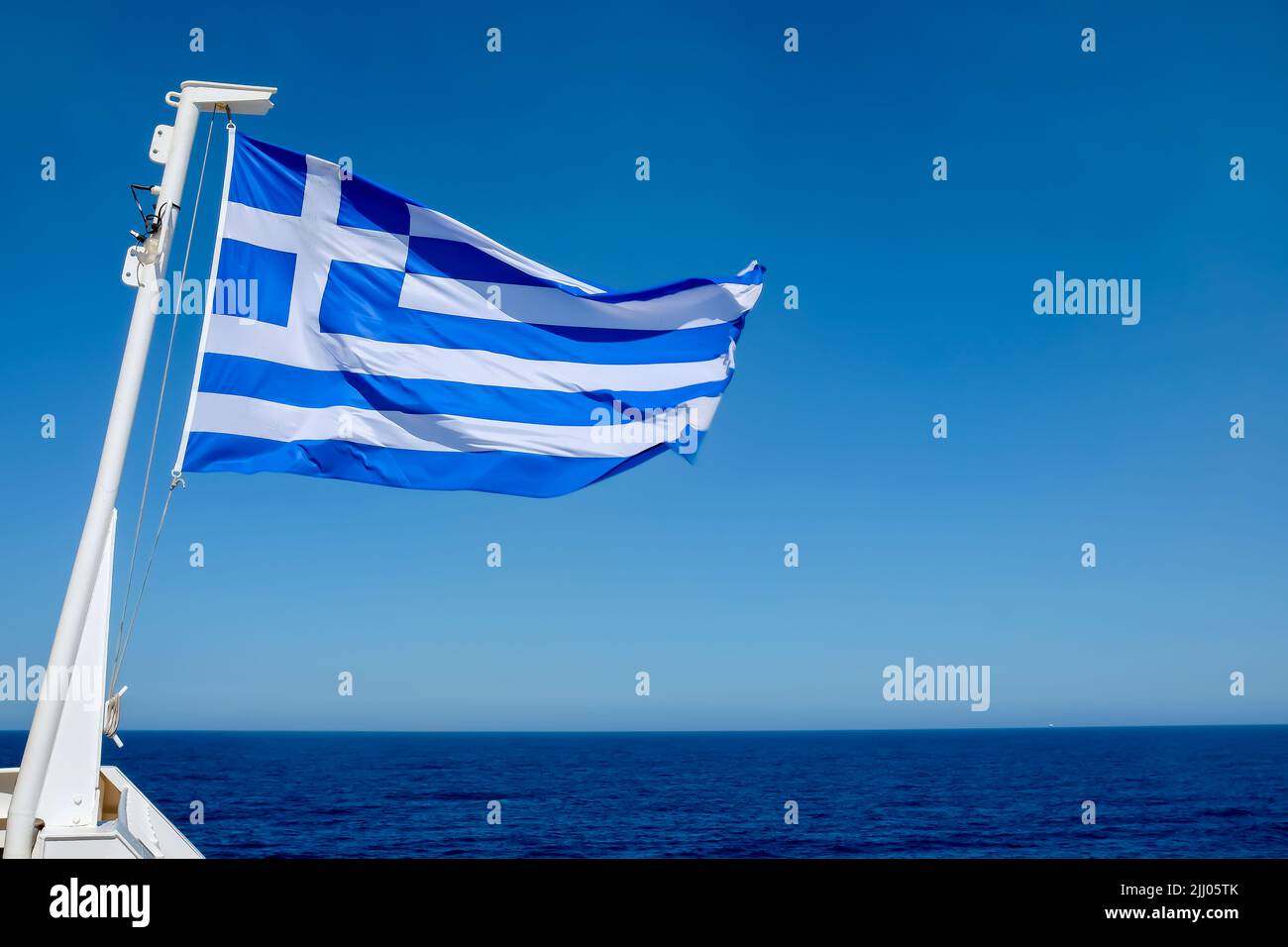 Huge greek flag of a ferry boat waving in the wind and the Aegean Sea ...
