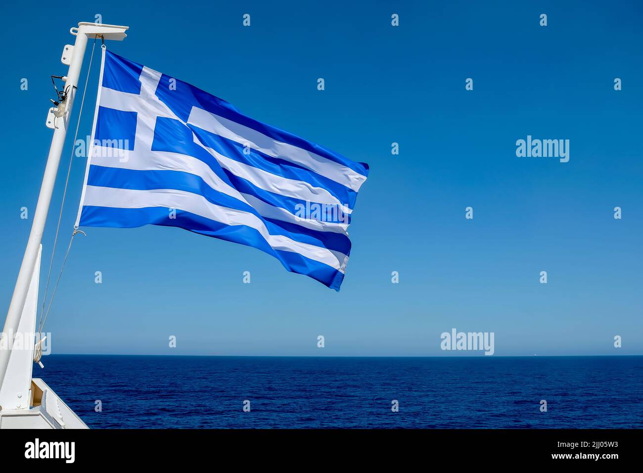 Huge greek flag of a ferry boat waving in the wind and the Aegean Sea ...