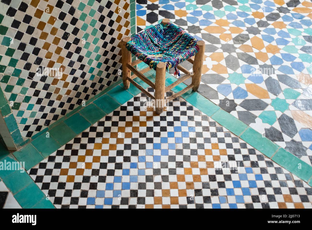 Blue wooden seat chair on a tile wall and floor squared pattern on a ...