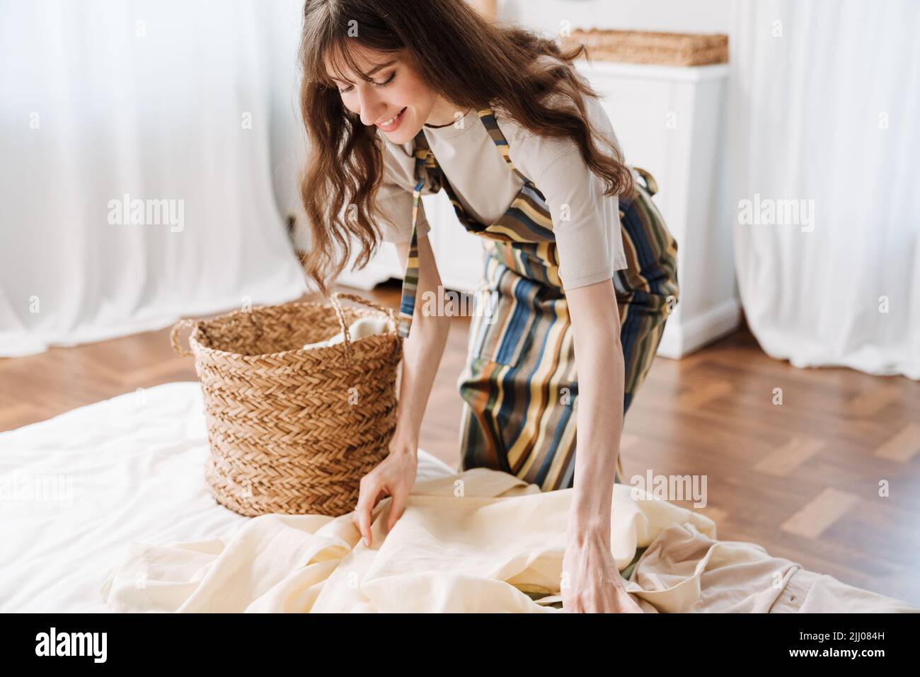 White young woman in apron smiling while doing housework at home Stock ...