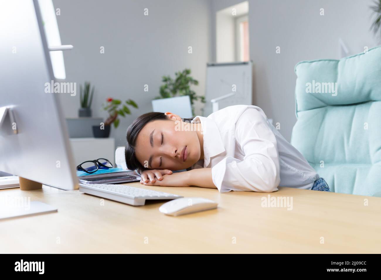 Young Asian businesswoman fell asleep at the desk on her hands in the ...
