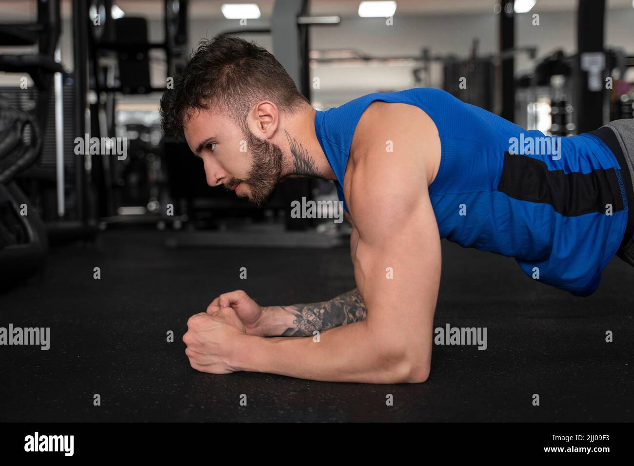 Handsome male with tattoos in his 20s doing plank in the gym Stock ...