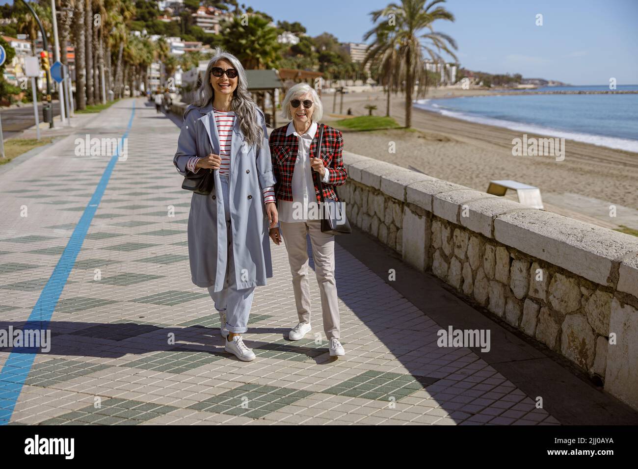 Two ladies on walk through promenade by sea Stock Photo - Alamy