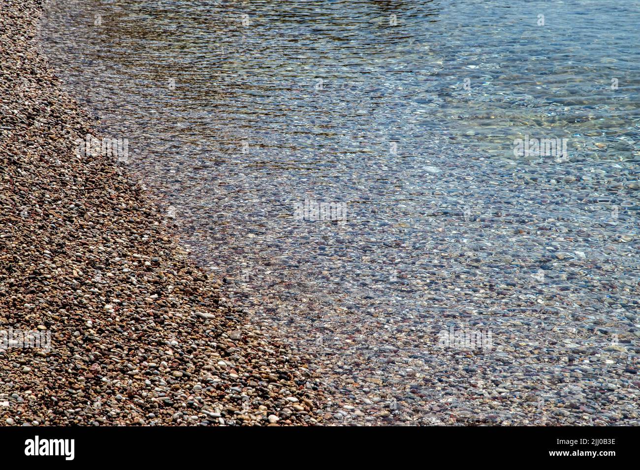 Clear calm sea waters meet pebble beach closeup as natural background ...