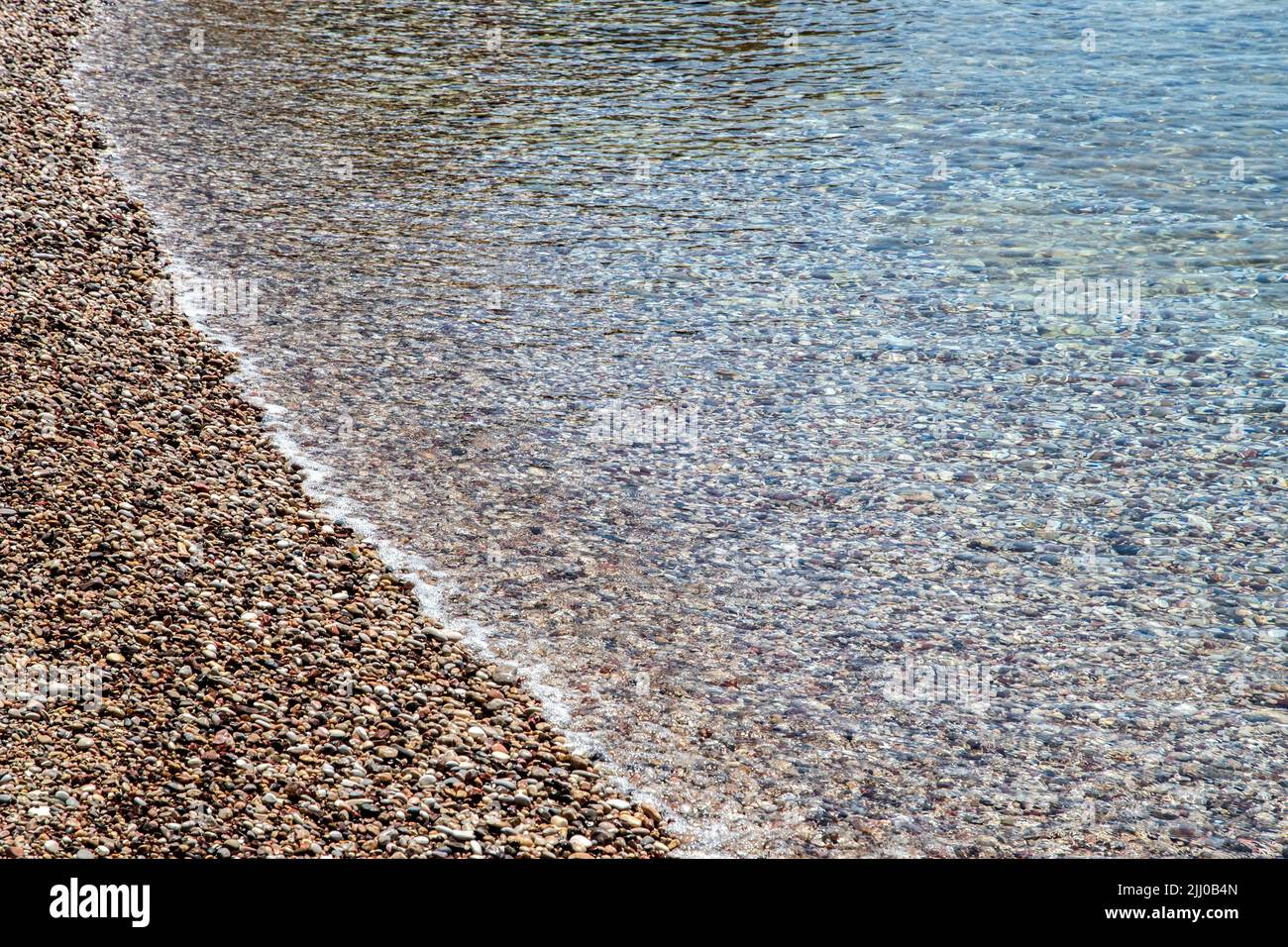 Clear calm sea waters meet pebble beach closeup as natural background ...