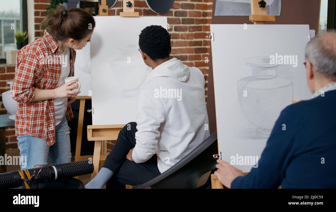 Young woman explaining artistic lesson to student in art class ...