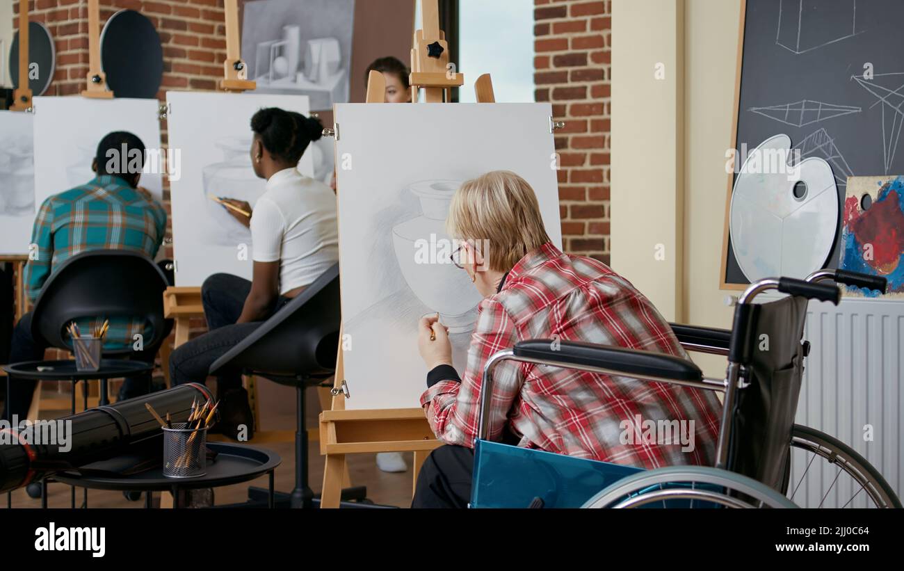 Senior woman in wheelchair drawing vase sketch with pencil on canvas ...