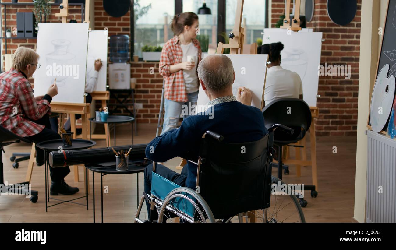 Old man with disability using pencil to draw masterpiece in art class ...