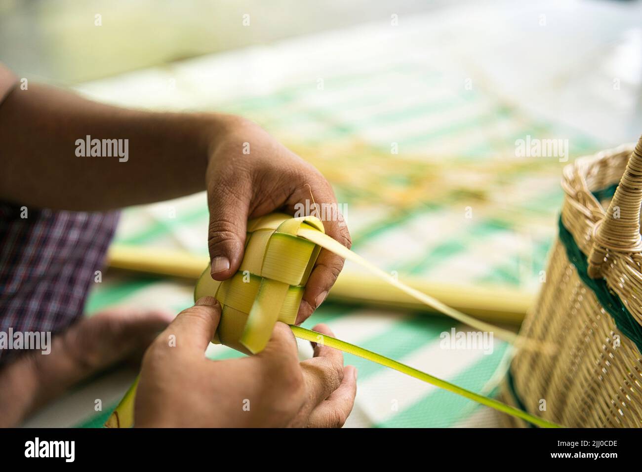 Weaving the coconut leaves making the ketupat, a traditional Malay ...