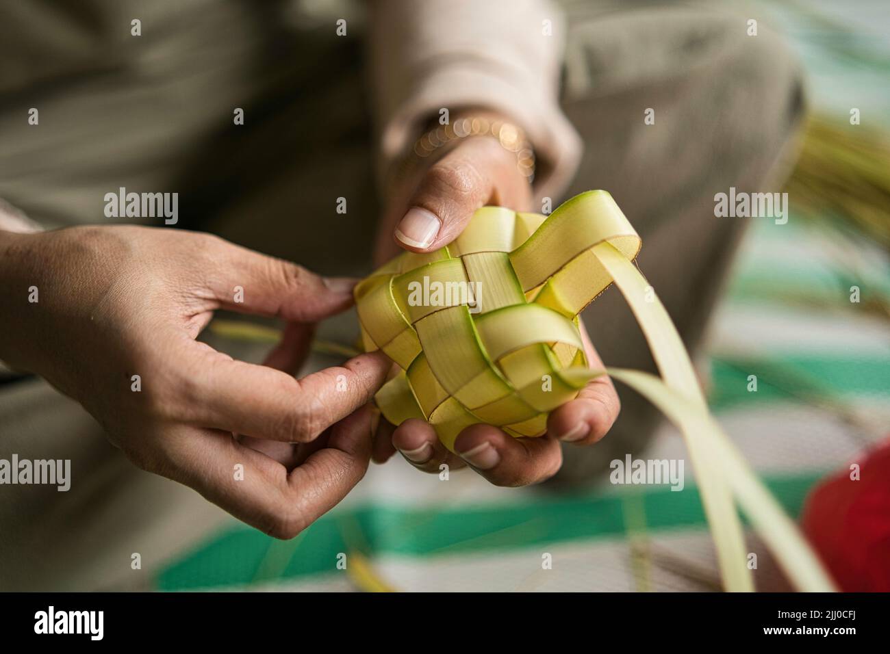 Weaving the coconut leaves making the ketupat, a traditional Malay ...