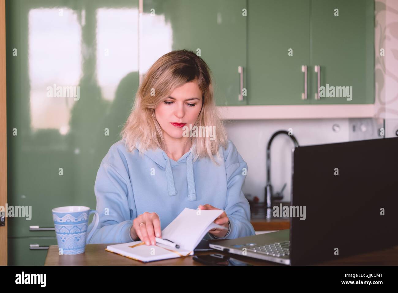 Blond woman working on her laptop from home Stock Photo - Alamy