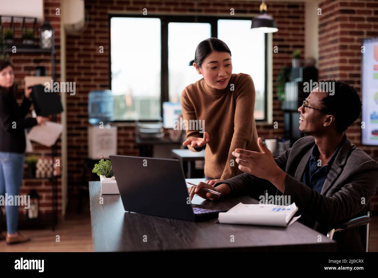 Diverse team of people working on laptop in disability friendly office ...