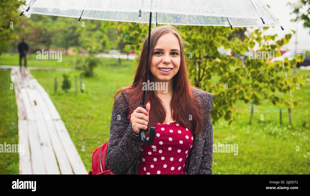 Young happy beautiful woman with transparent umbrella in rain, standing ...