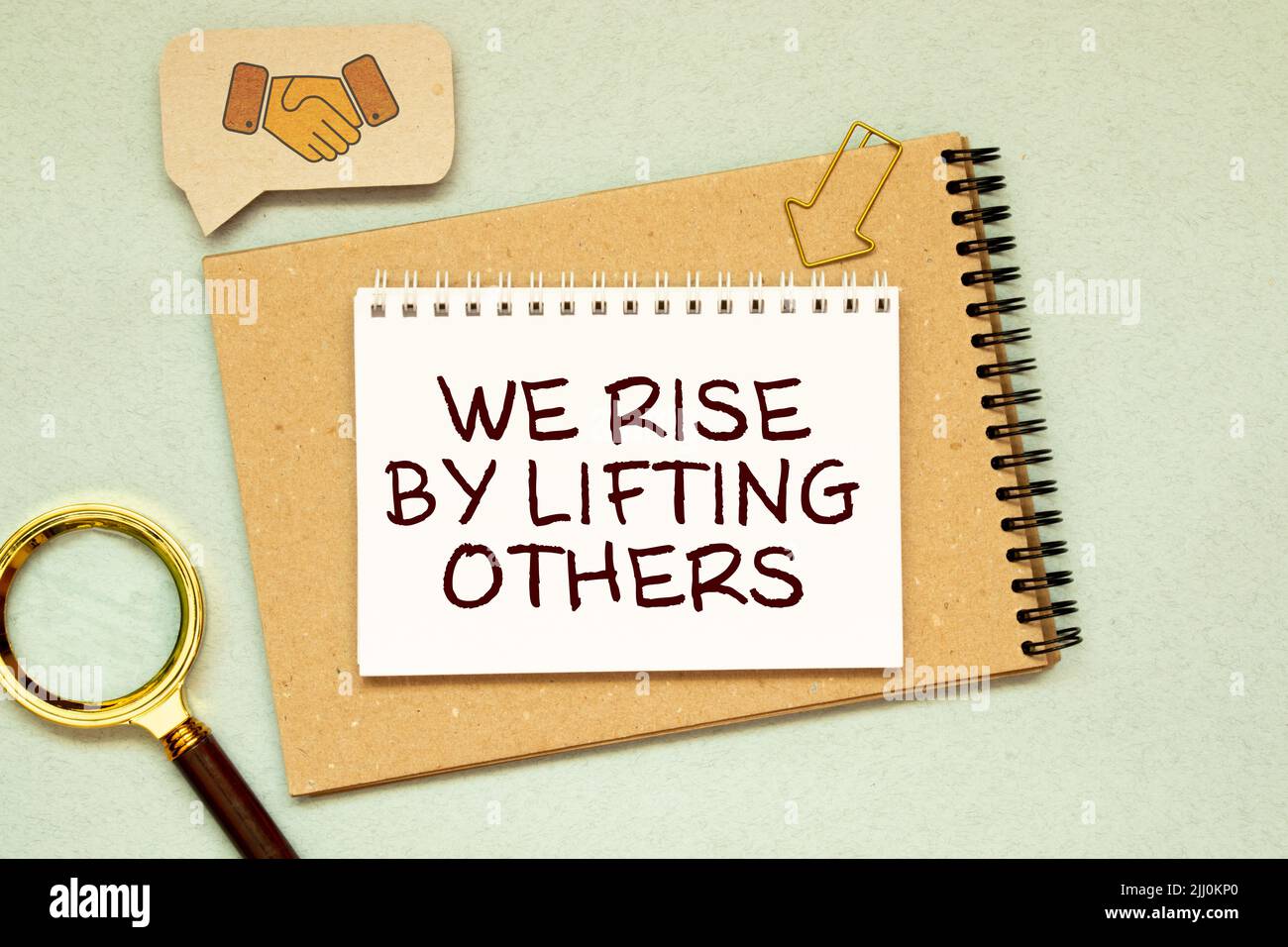 Motivation concept.Text WE RISE BY LIFTING OTHERS writing on notebook ...