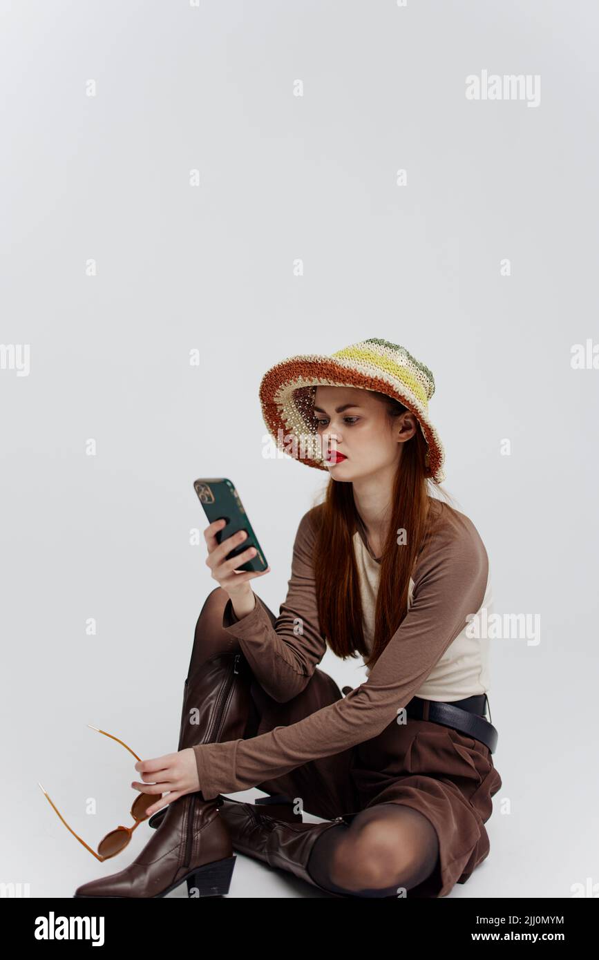 A focused lady in a hat is texting on the phone while sitting on the ...