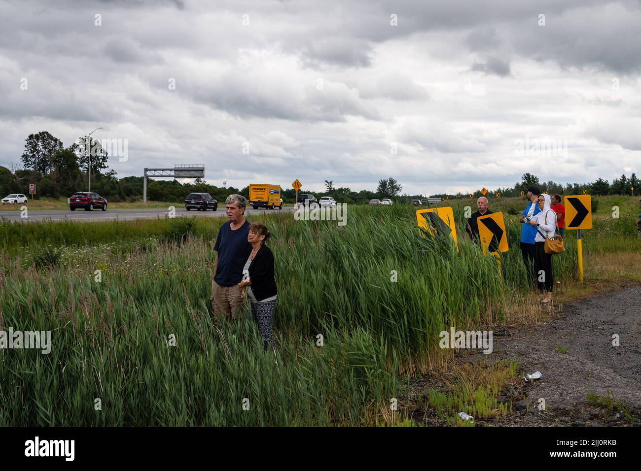 People look at a procession of motorcycles along the highway. Hundreds ...