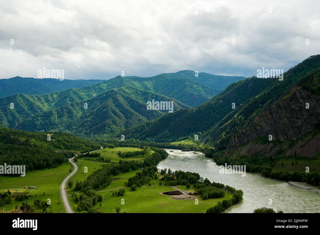 Mountain river flows through a green valley between mountains and ...