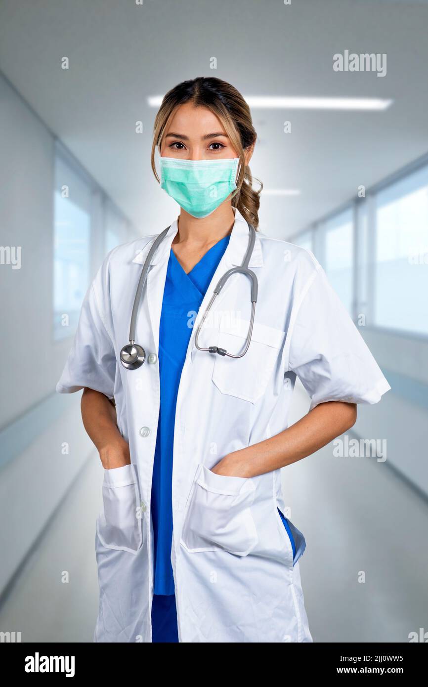 Female doctor in uniform wearing face mask standing with her hand in ...