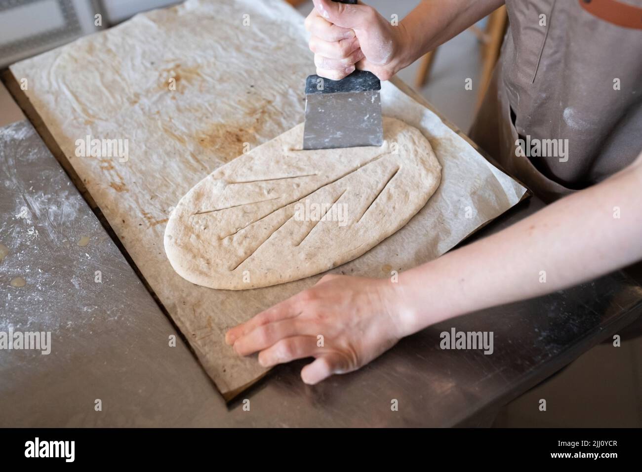 A baker shapes and cuts traditional French Fougasse bread. Front view ...