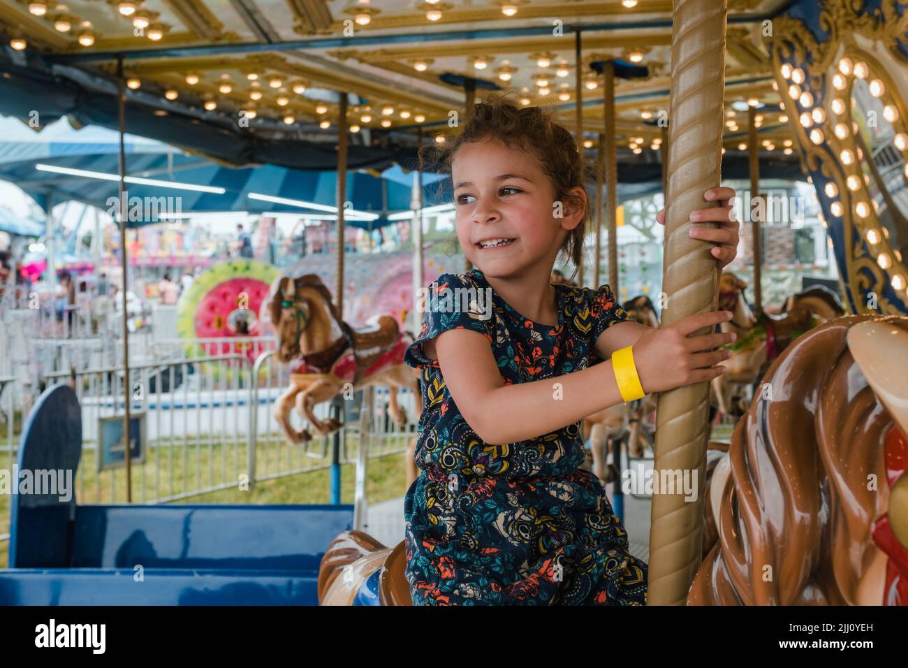 Cute multiracial girl riding on carousel Stock Photo - Alamy