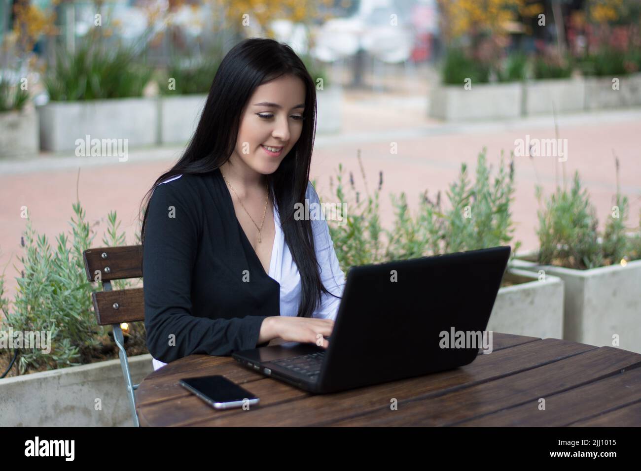 Young woman working outdoor, using laptop computer in the city street ...
