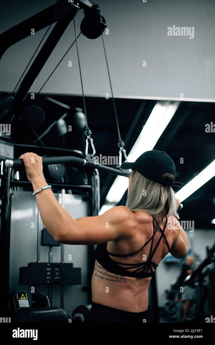 Muscular woman using machine at gym wearing black workout clothi Stock ...