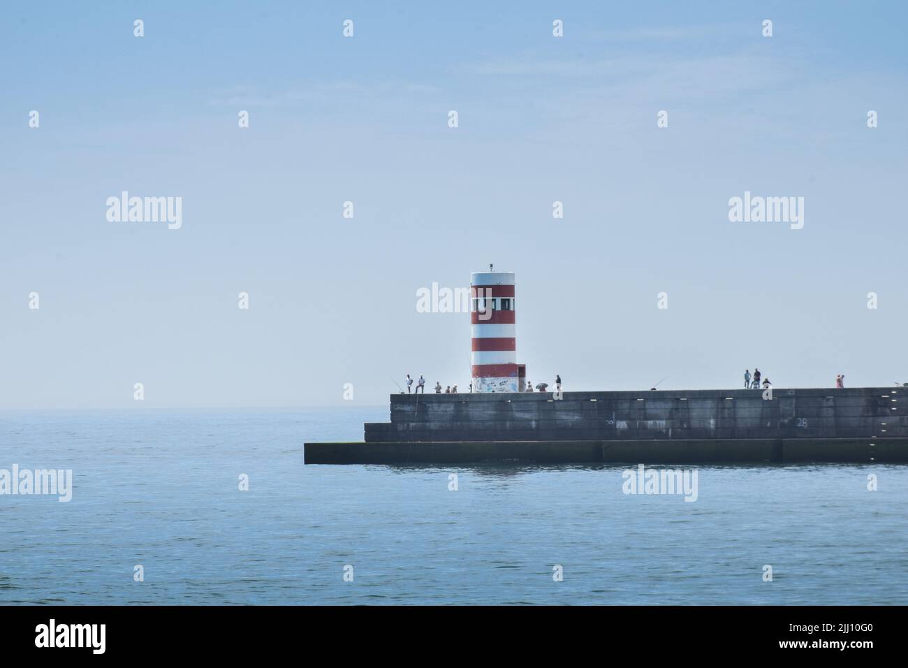 lighthouse on the pier with fisherman Stock Photo - Alamy