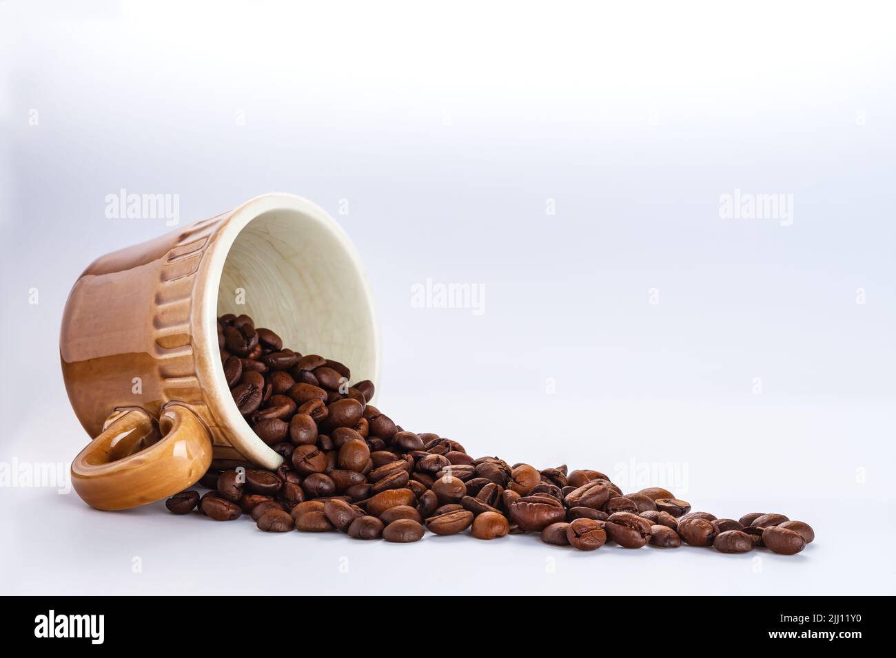 Roasted coffee beans spill out of Coffee mug overturned on white ...