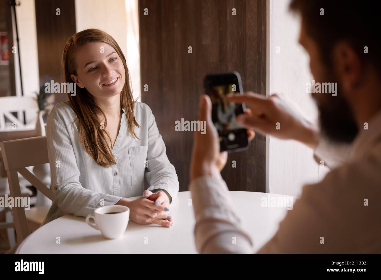 couple in love sitting in cafe, male photographer photographing woman ...