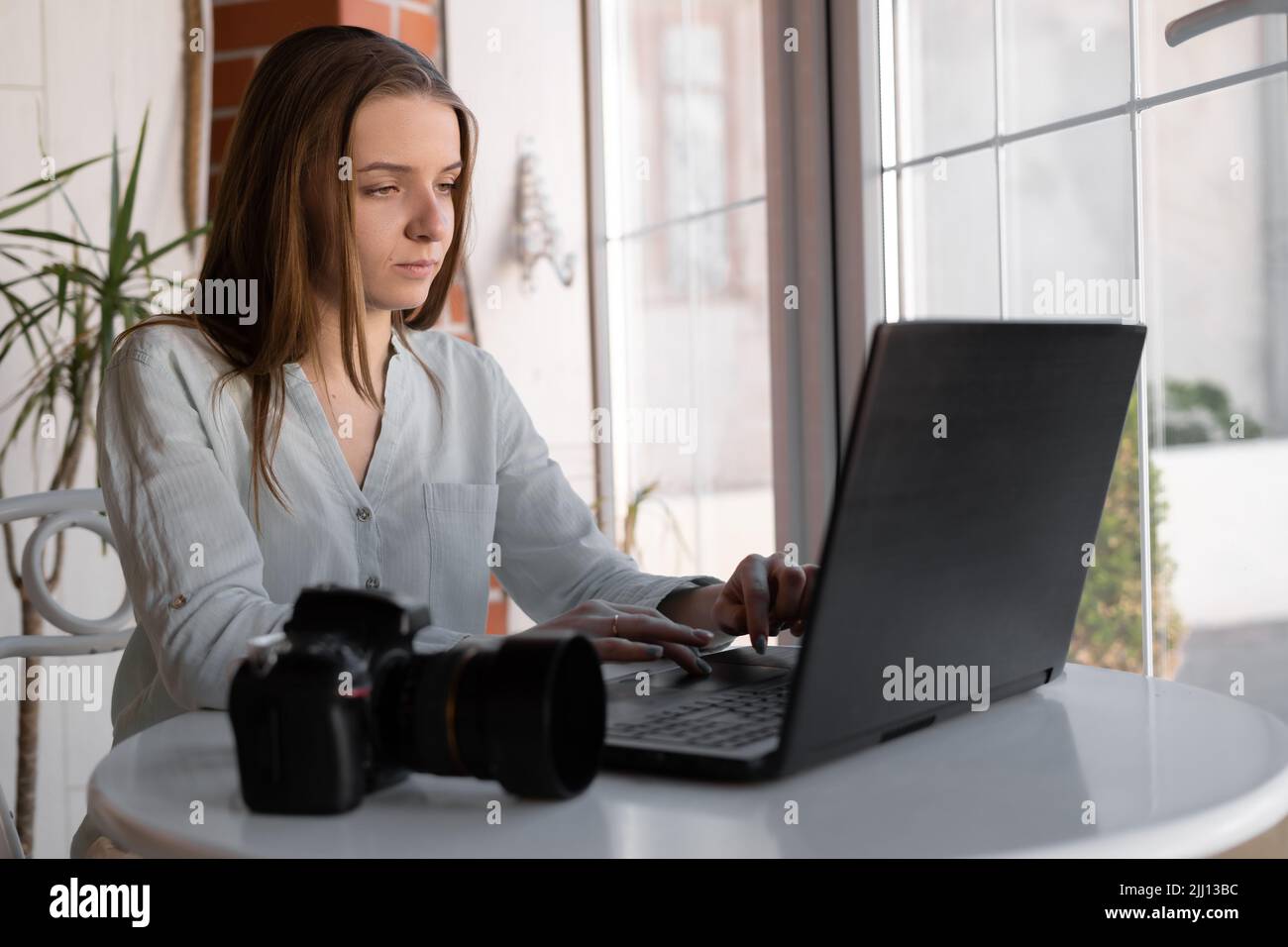 Photographer girl using laptop sitting at cafe, typing on keyboard ...