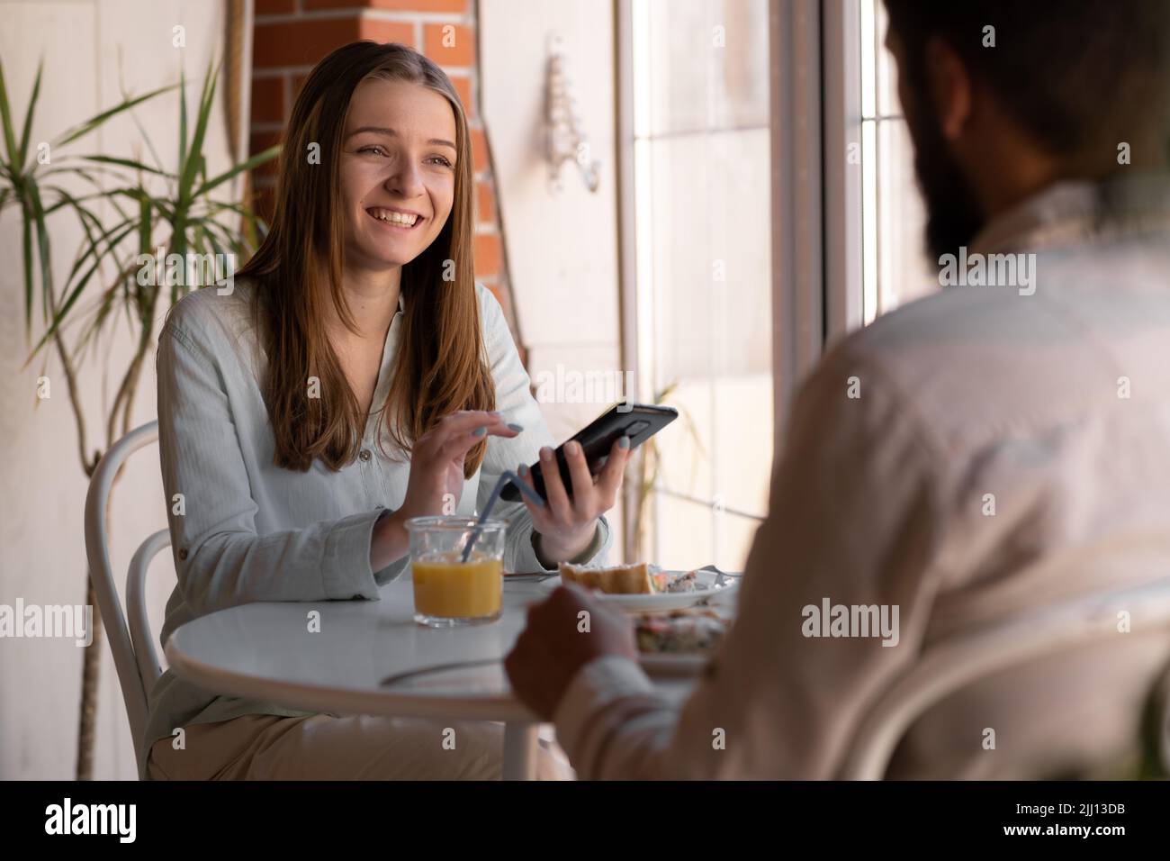 young joyful couple using cellphones and laughing while having ...