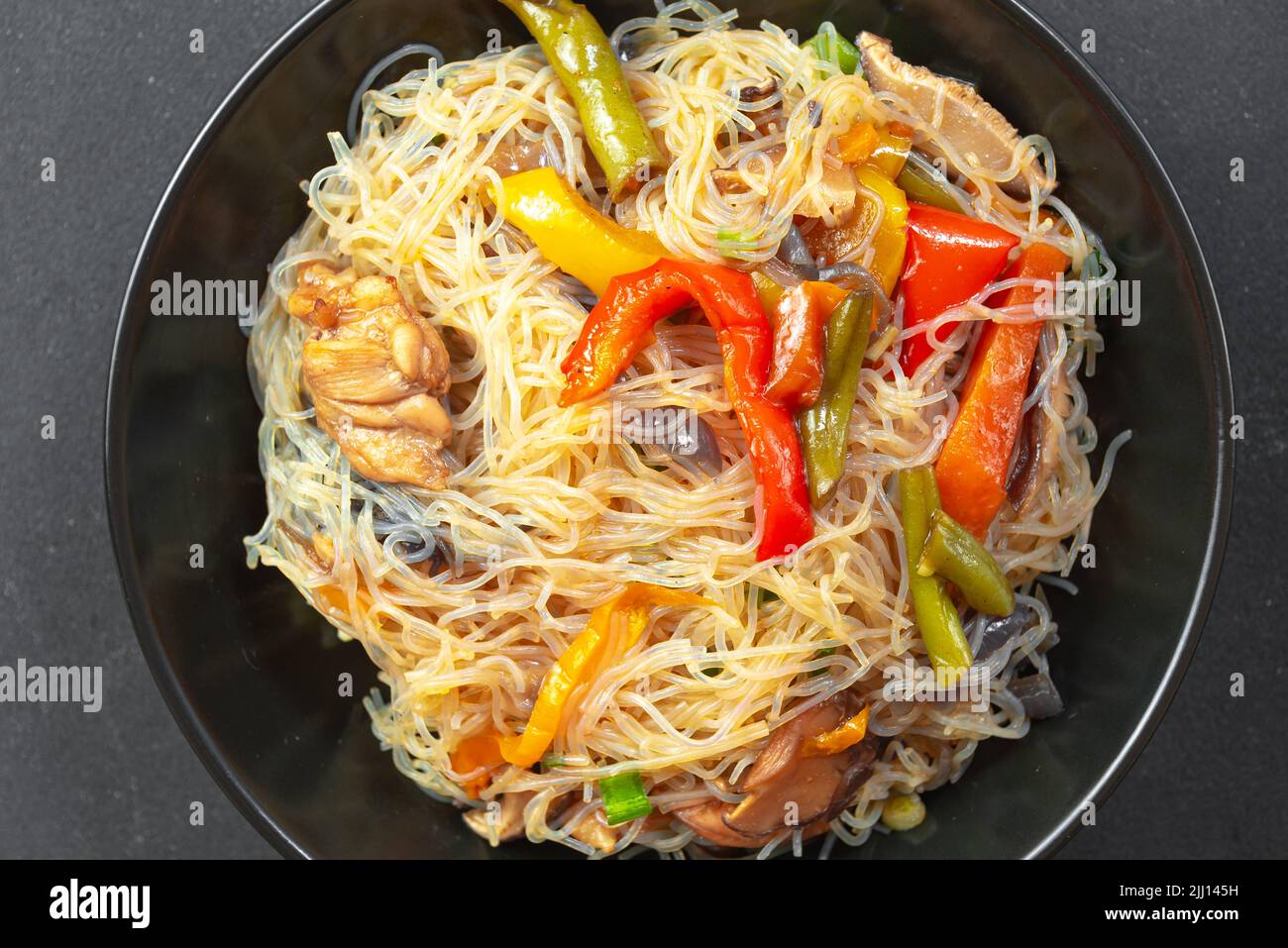 Chinese noodles with vegetables in a black plate. Asian rice or crystal ...