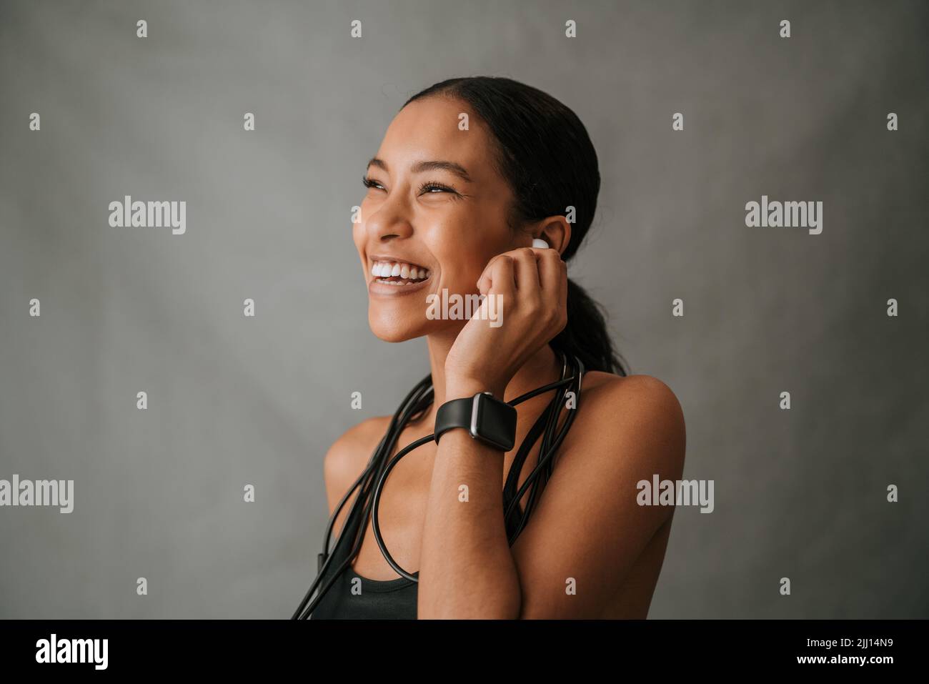 Close up Young Multiethnic female smiling and listening to her ear pods ...